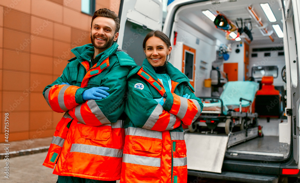 Two paramedics in uniforms stand with their arms crossed in front of a ...