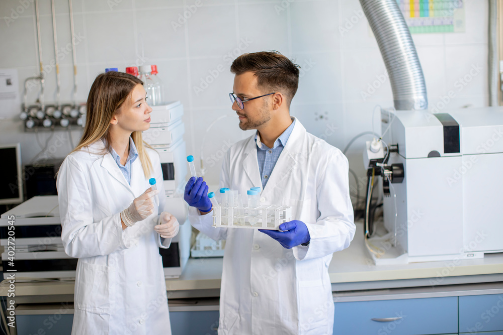 Group of young researchers analyzing chemical data in the laboratory ...