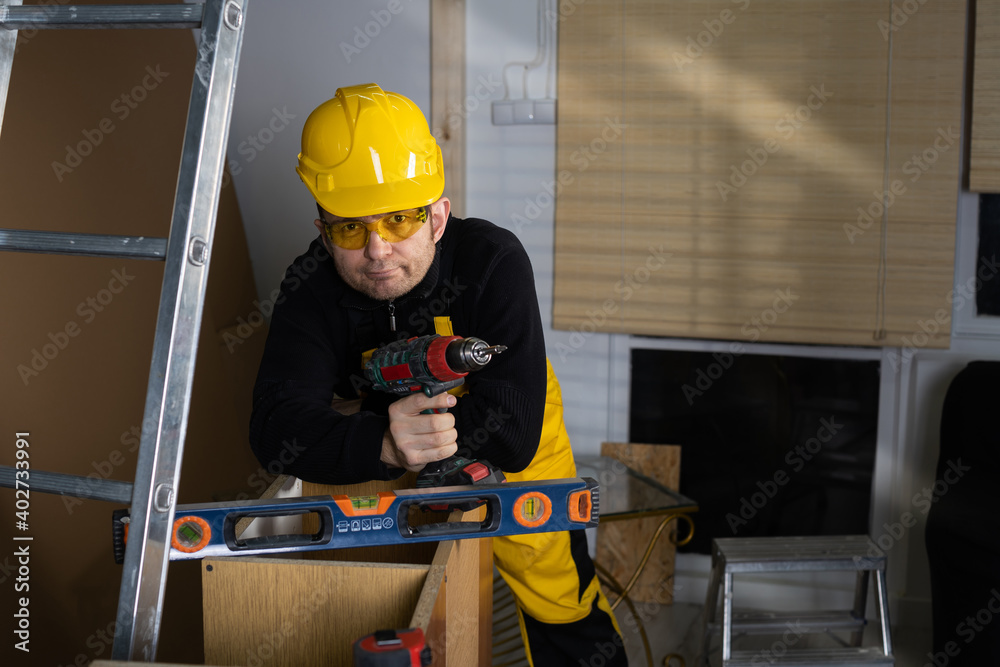 A general construction worker with a cordless screwdriver in hand is ...