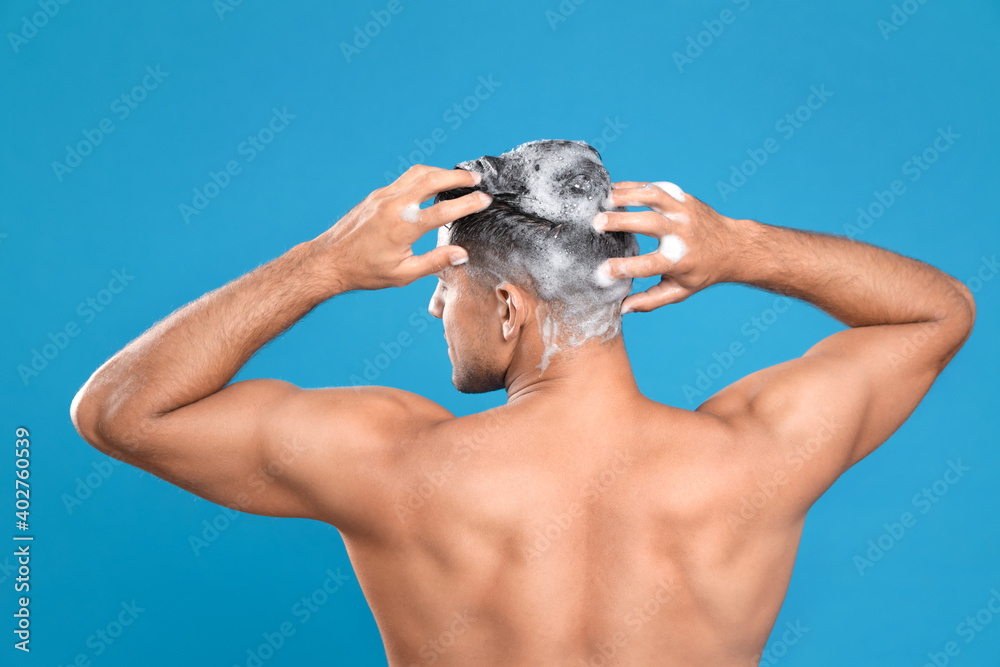 Handsome man washing hair on light blue background, back view Stock ...