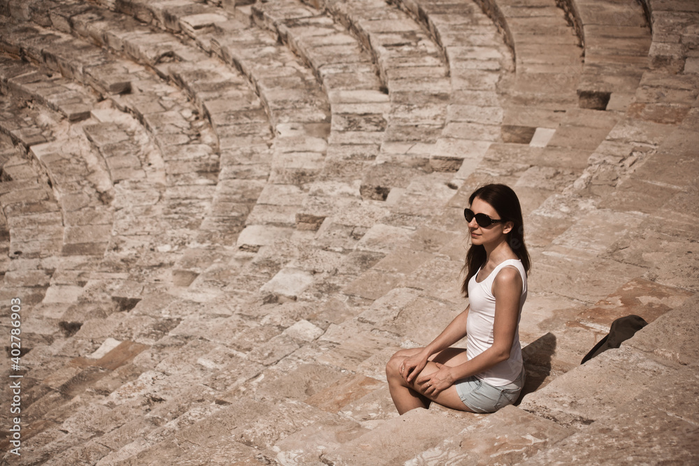 Foto de Young woman sitting in ancient Odeon amphitheatre in Paphos ...