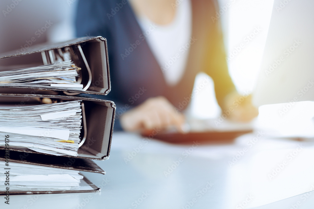 Binders with papers are waiting to be processed by business woman or ...