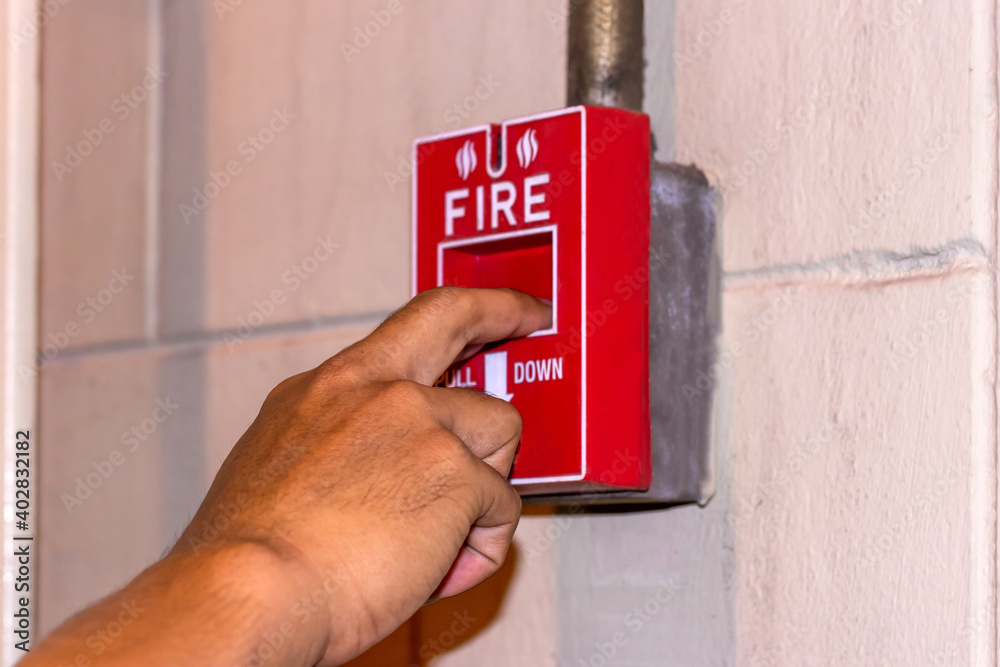 Hand pulling down the manual fire alarm station in case of fire ...