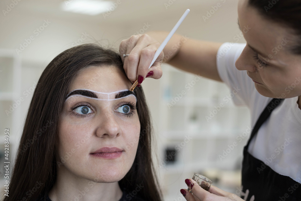 The master draws auxiliary lines between the eyebrows with a white ...