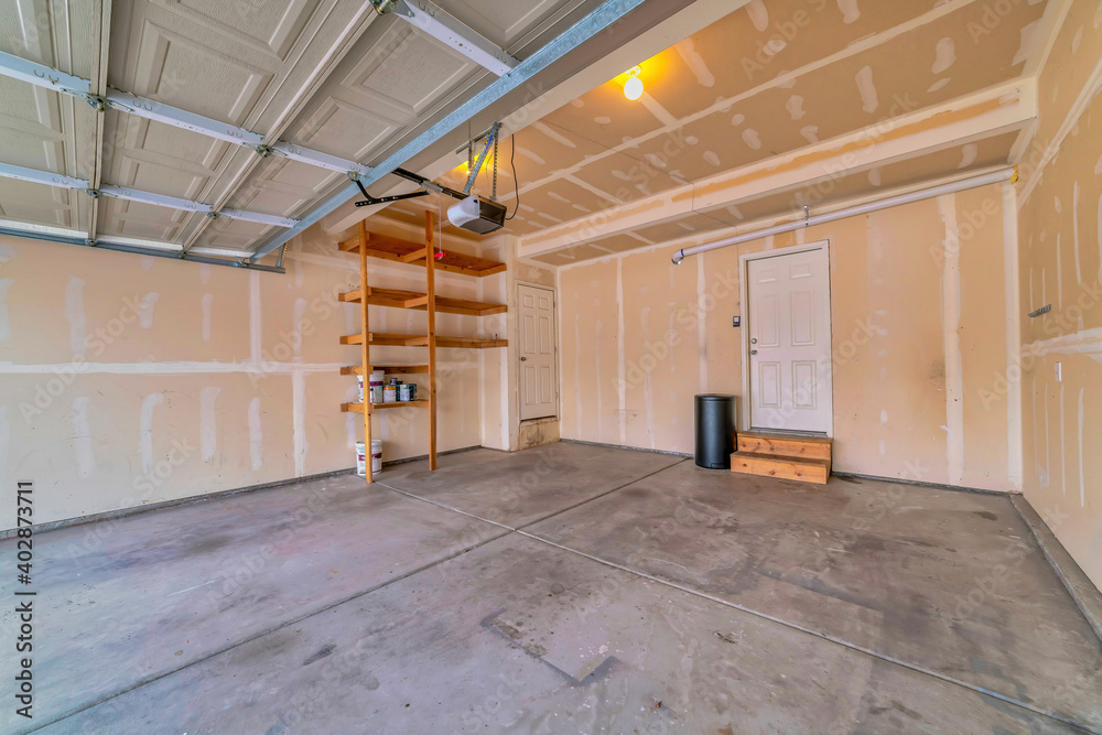 Interior of empty attached garage with white door that leads inside the ...