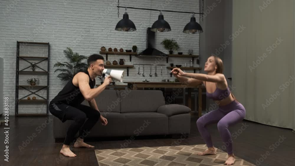 A personal trainer yells into a megaphone, making the girl do squats ...