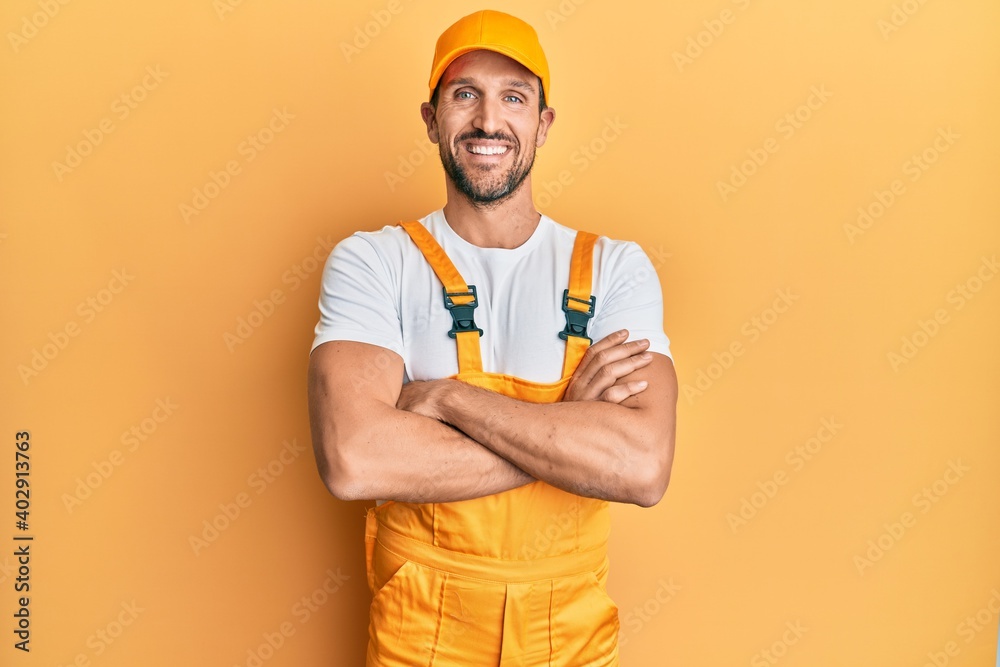 Young handsome man wearing handyman uniform over yellow background ...