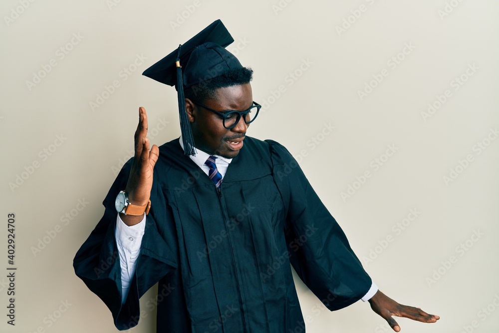 Handsome black man wearing graduation cap and ceremony robe dancing ...