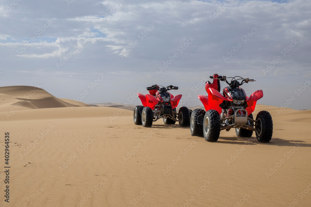 two red quad bikes standing on top of a dune in the desert Stock Photo ...
