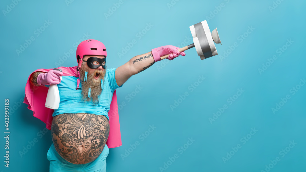 Horizontal shot of plump man superhero stretches arm with plunger ...