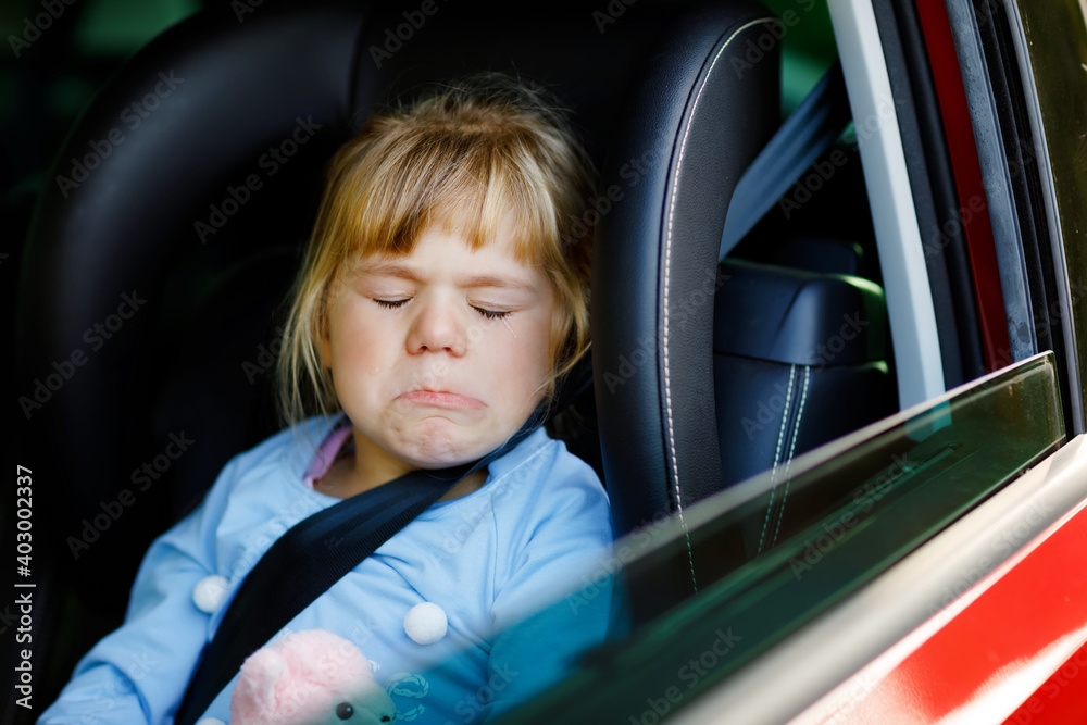Sad upset little kid girl sitting in car in traffic jam during going ...