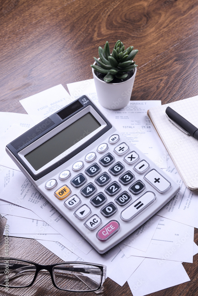 Calculator keypad with checks from the store from shopping on a wooden ...