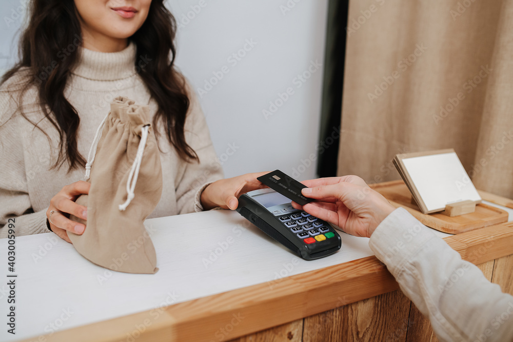 Cropped image of female customer making a purchaise, paying with her ...