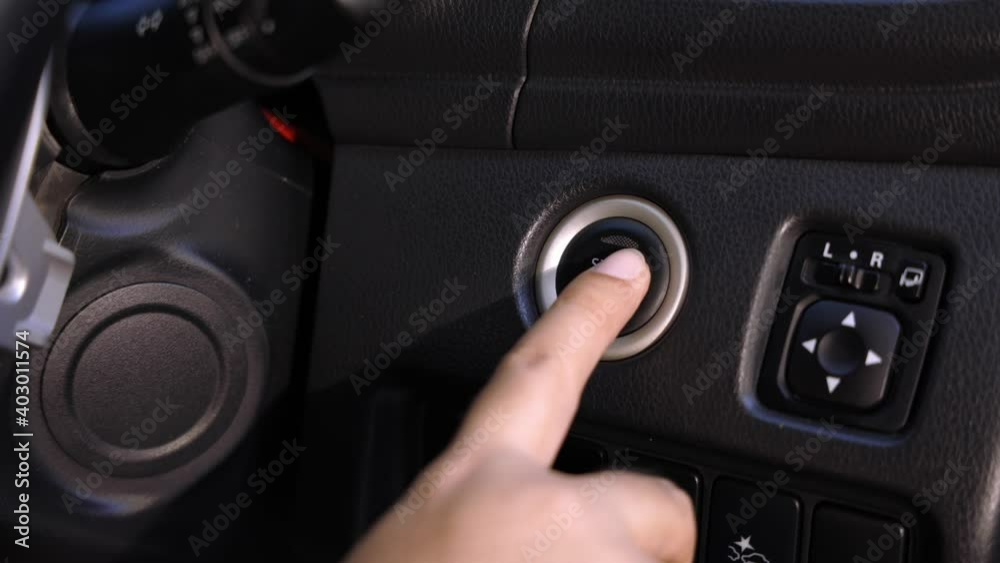 Fingers are pressing the car start button. Young man starting to drive ...
