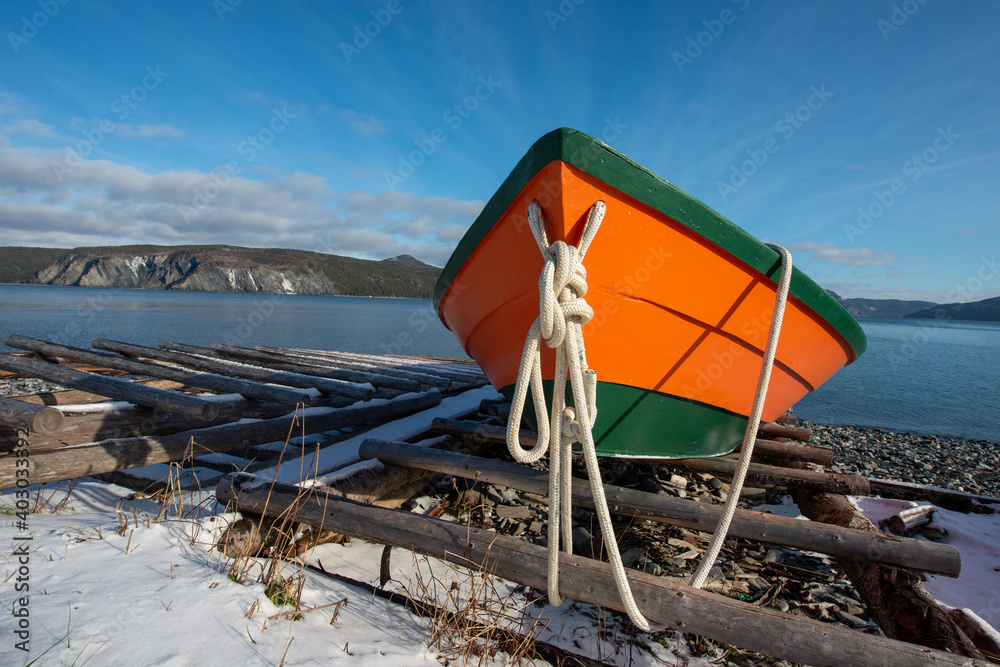 Bright orange and green colourful wooden boat on a beach. There is a ...
