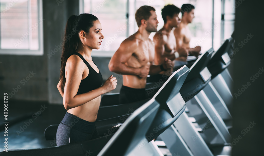 attractive young woman and female running on treadmill machine at gym ...