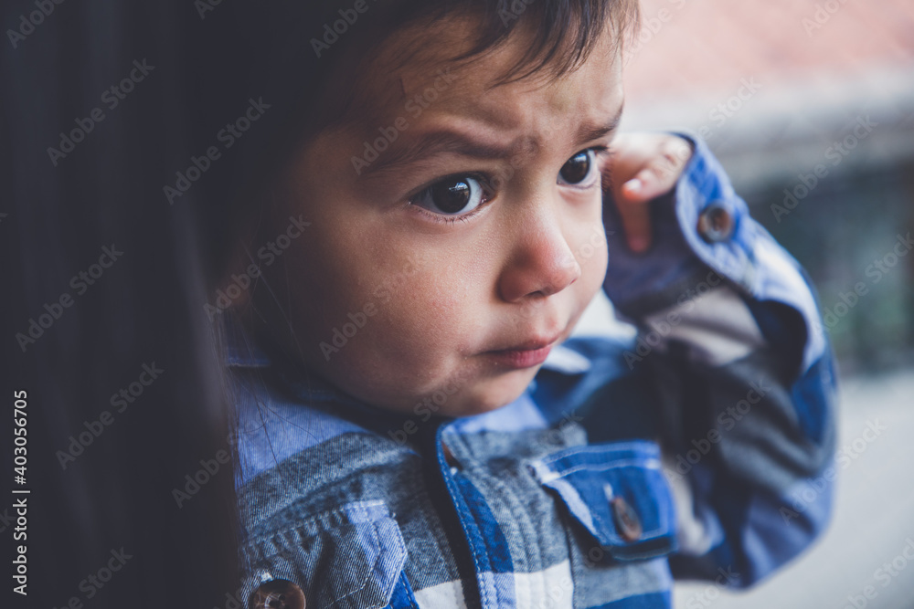 Closeup face of cute little boy sitting alone with curious face in ...