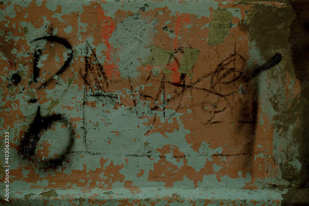 Old dilapidated wall texture with scribbled graffiti on a flaking paint ...