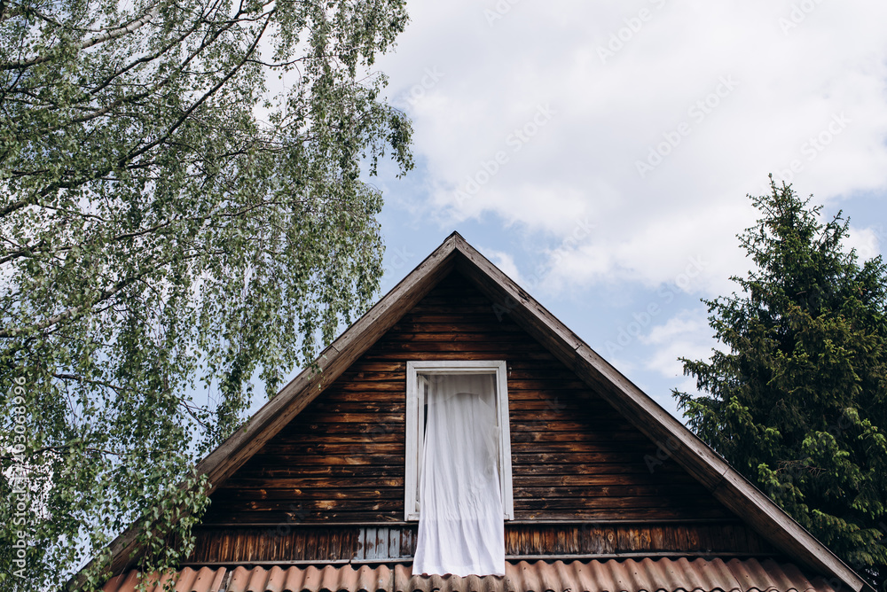 Wooden old unpainted house with a triangular sloping roof, next to the ...