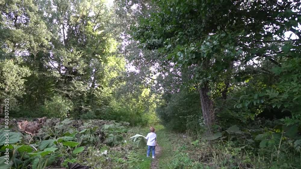 A boy in a white t-shirt and blue jeans. The boy is holding a large ...