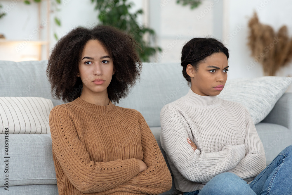 Conflict between two best friends. Women crossed arms, sitting on floor ...