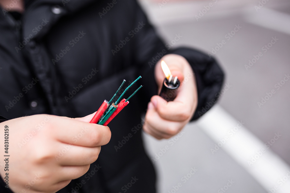 Boy lighting up several firecrackers in his hand using lighter. Kid ...