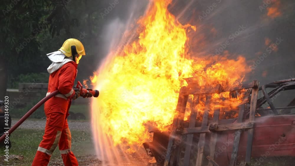 Brave firefighter in fire protection suit on safety rescue duty spray ...