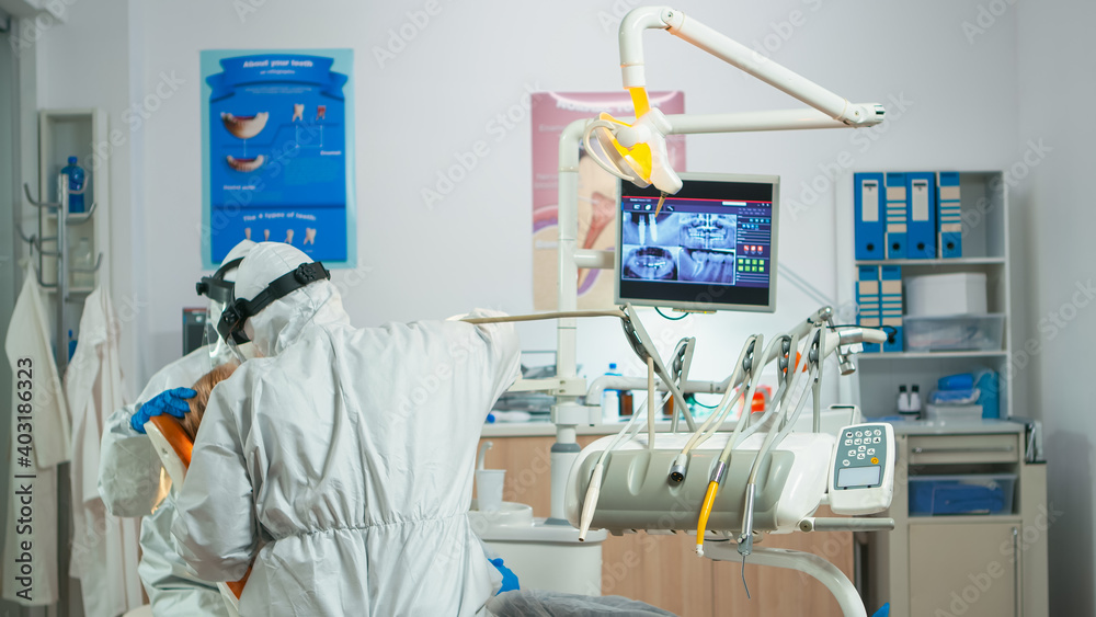 Dentist with face shield working in dental unit during covid-19 ...