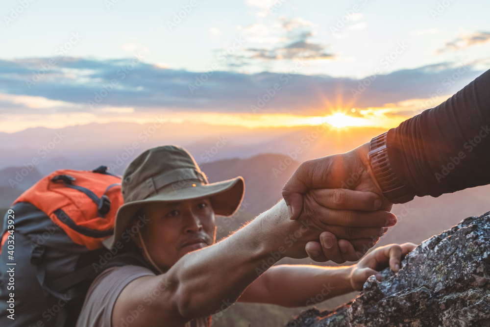 Foto de Two Male hikers climbing up mountain cliff and one of them ...