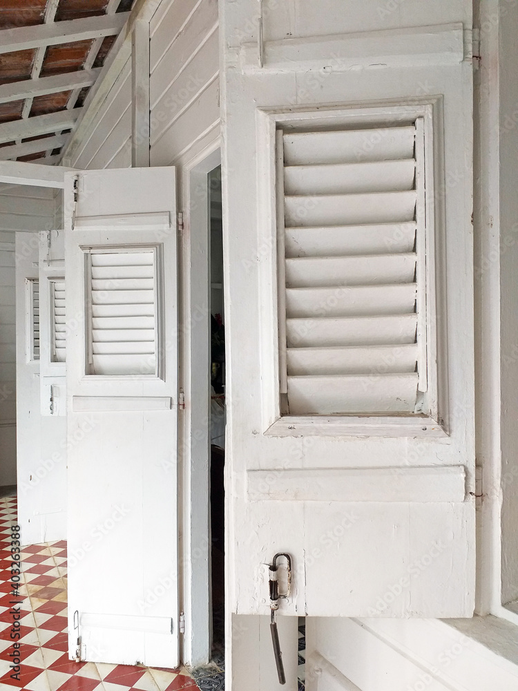 Perspective view of white wooden shutters and storm doors in ...