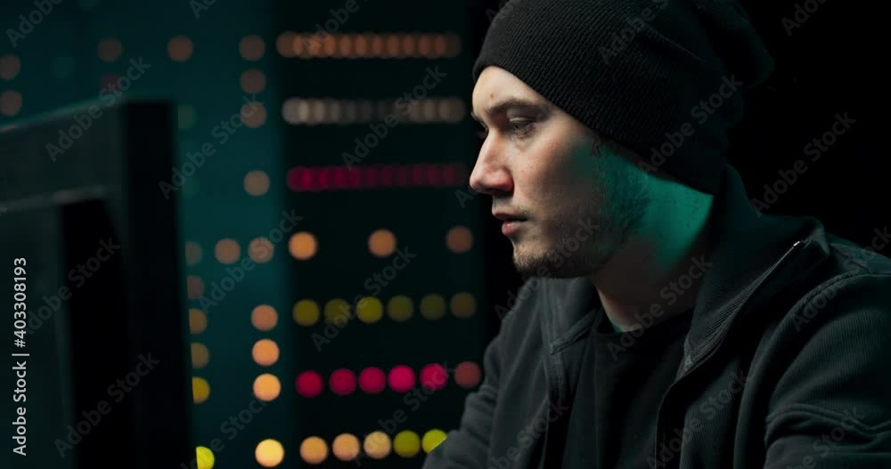 Concentrated hacker in sweatshirt and cap Breaks into corporate servers ...