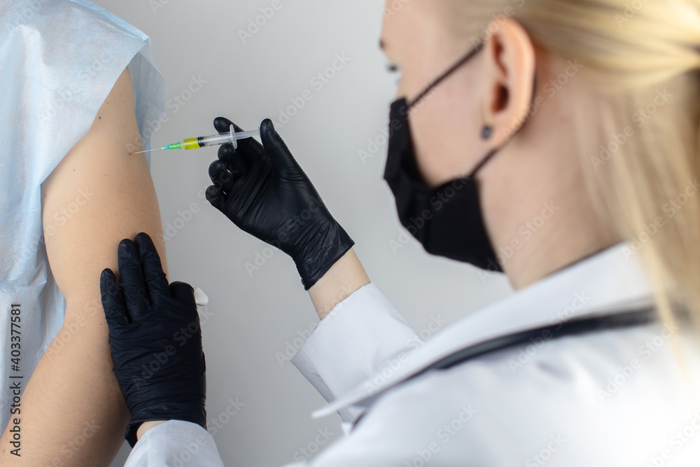 Infectious disease doctor gives the patient a medical vaccination in ...