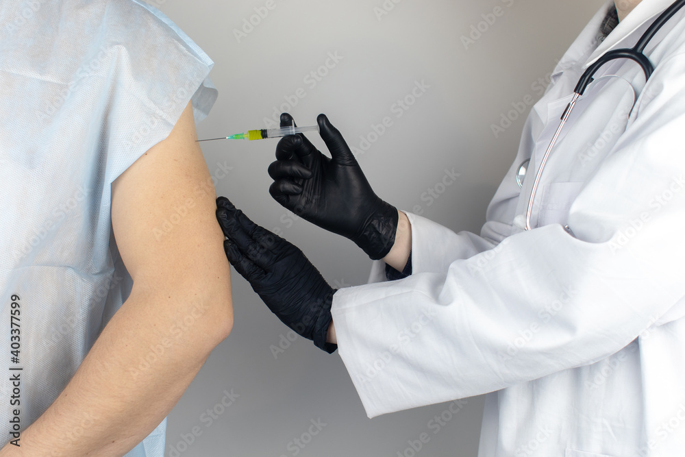 Infectious disease doctor gives the patient a medical vaccination in ...