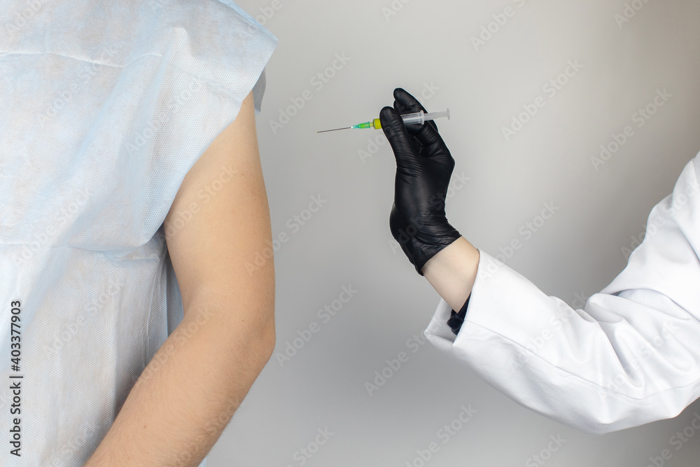 Infectious disease doctor gives the patient a medical vaccination in ...