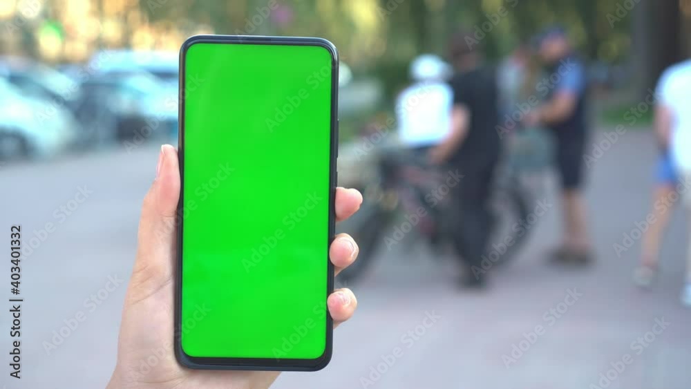 Close up hands woman holding phone with vertical green screen on busy ...