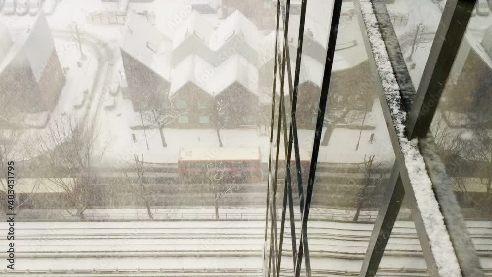 Snow falling from a high rise office building overlooking a London bus ...