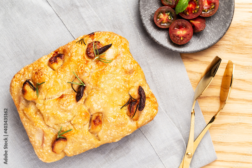 Italian focaccia with confit garlic cloves and rosemary, alongside a ...