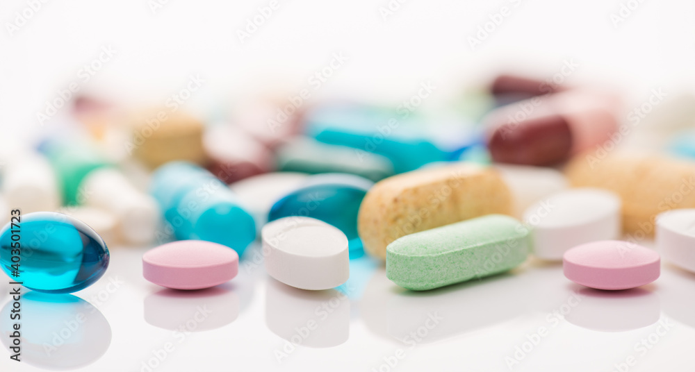Close up photo of different shape multicolored pills lying on white ...