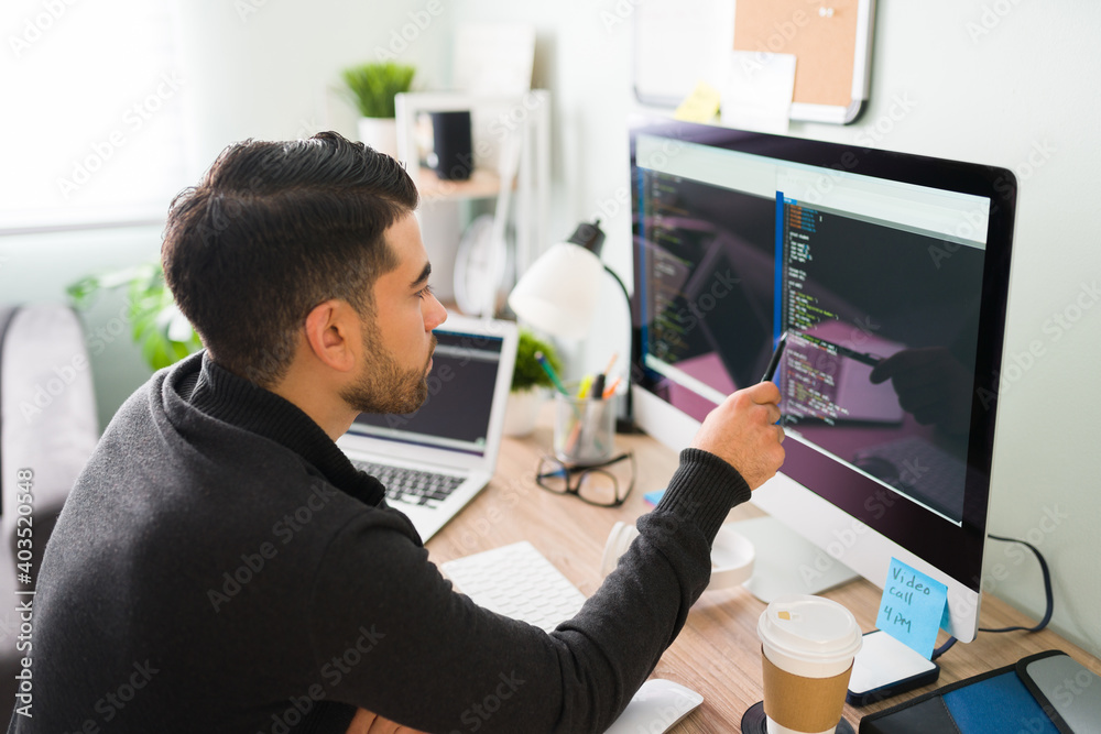 Young man at the computer checking that his coding is correct Stock ...