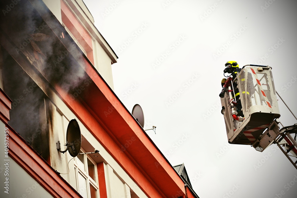 Fire fighter at truck ladder at a fire in a high-rise apartment ...