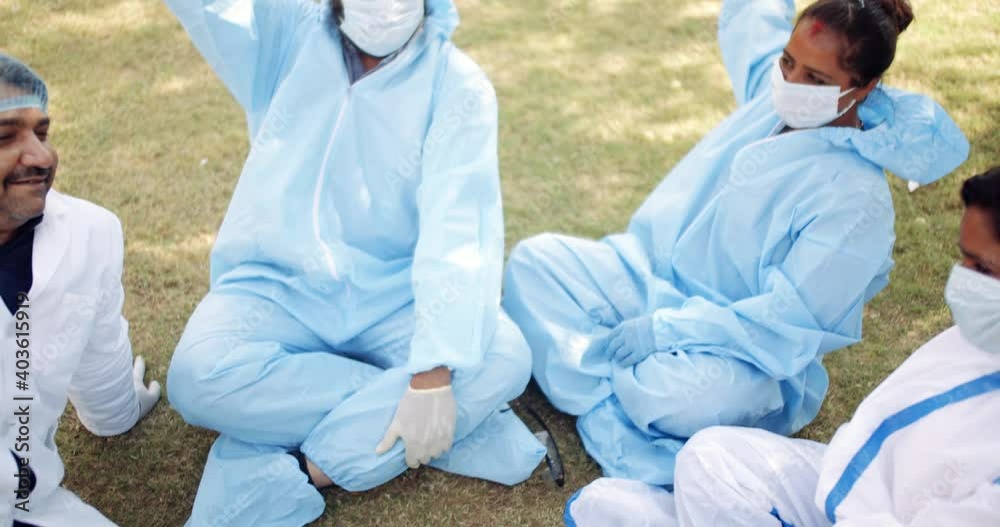 Group of healthcare workers in ppe suits seated bring hand palms ...