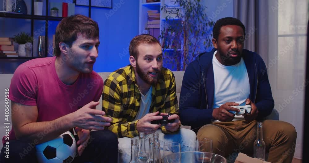 Cheerful happy African American and Caucasian men playing video games ...