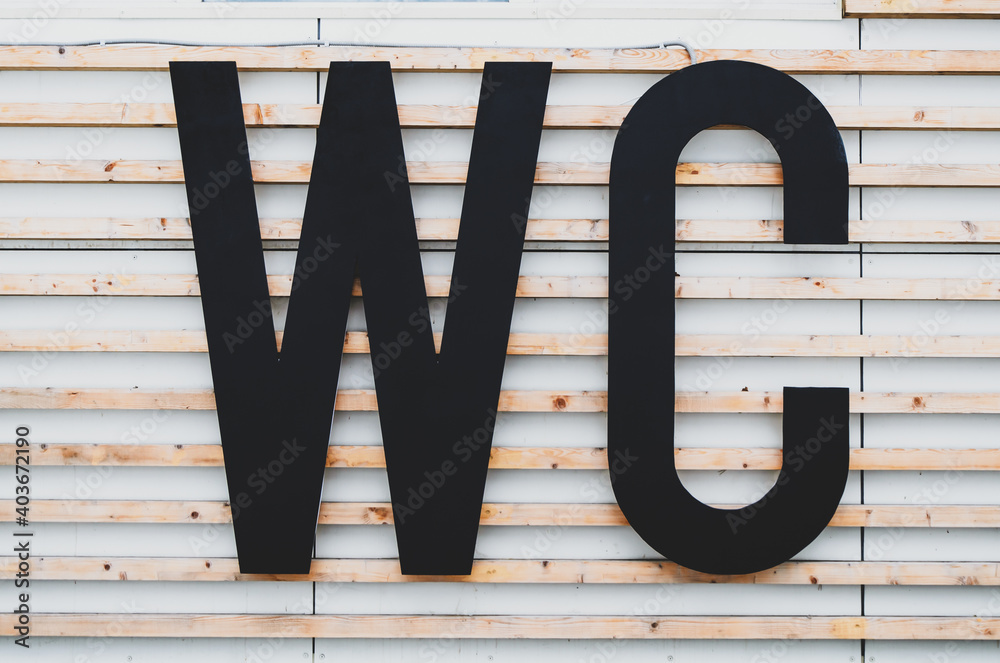 Large letters WC on facade of building with wood paneling. Public ...