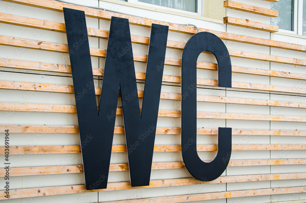 Large letters WC on facade of building with wood paneling. Public ...