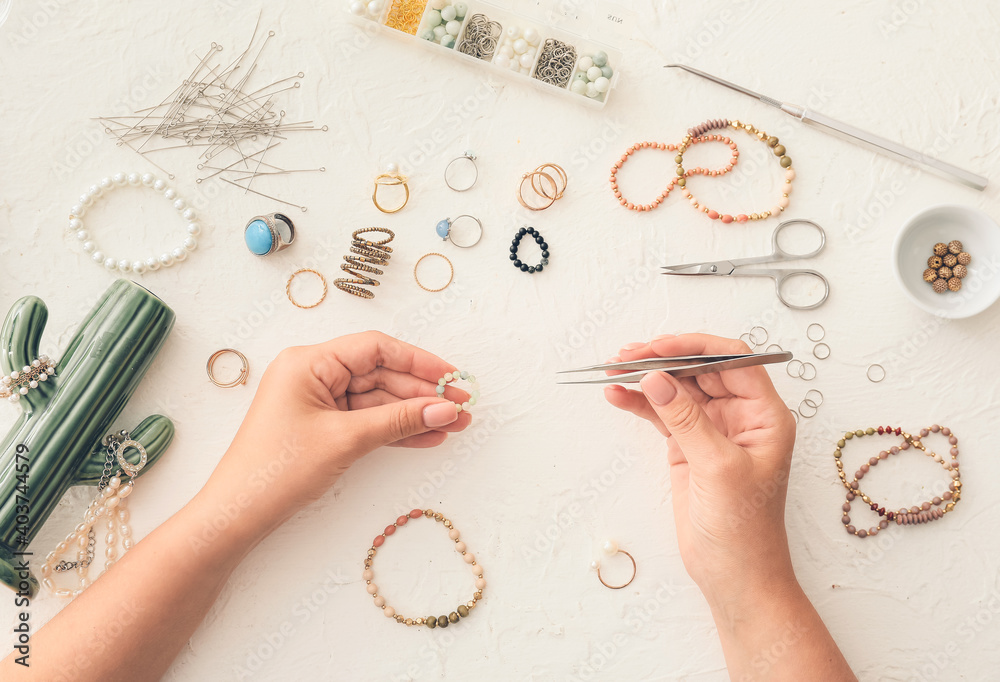 Female designer making jewelry on light background Stock Photo | Adobe ...