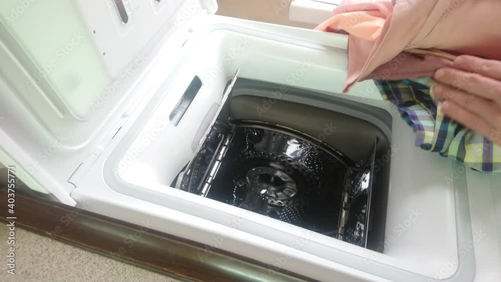 Woman loads dirty clothes into a vertical washing machine Stock Video ...