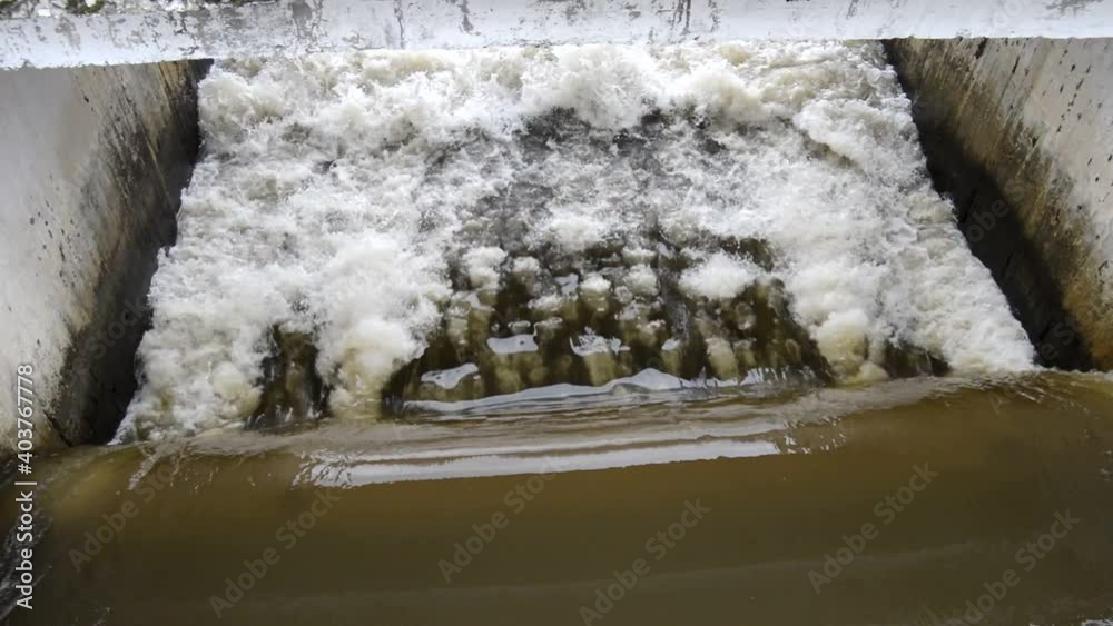 River water with high pressure flows over a small dam channel during ...