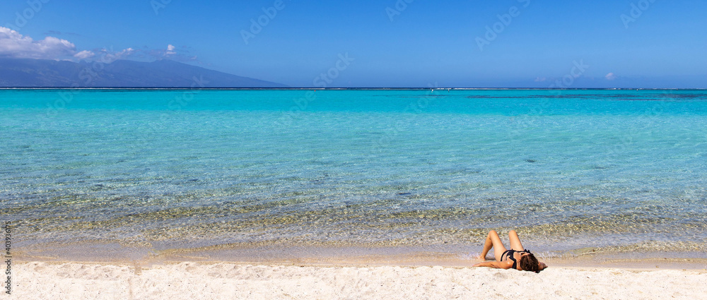 Woman wearing bikini laying down on sandy beach sunbathing during a ...
