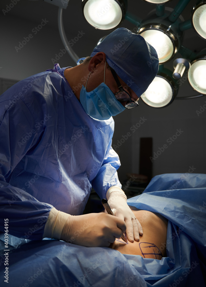 Foto de Plastic surgeon in blue surgical uniform using scalpel and ...