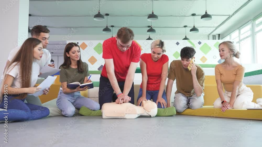 CPR class with male instructor speaking and demonstrating help, giving ...